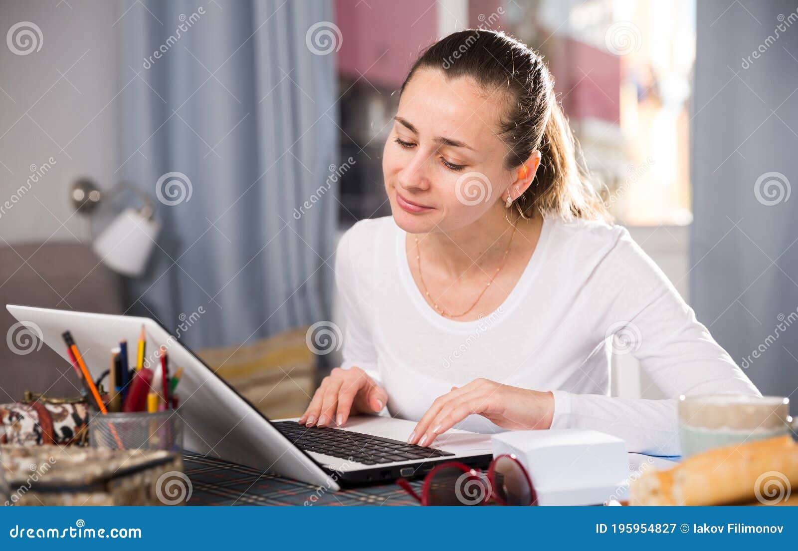 Smiling Girl Sitting at Table at Home Calculating Domestic Finances and ... Smiling Girl Sitting at Table at Home Calculating Domestic Finances and ...