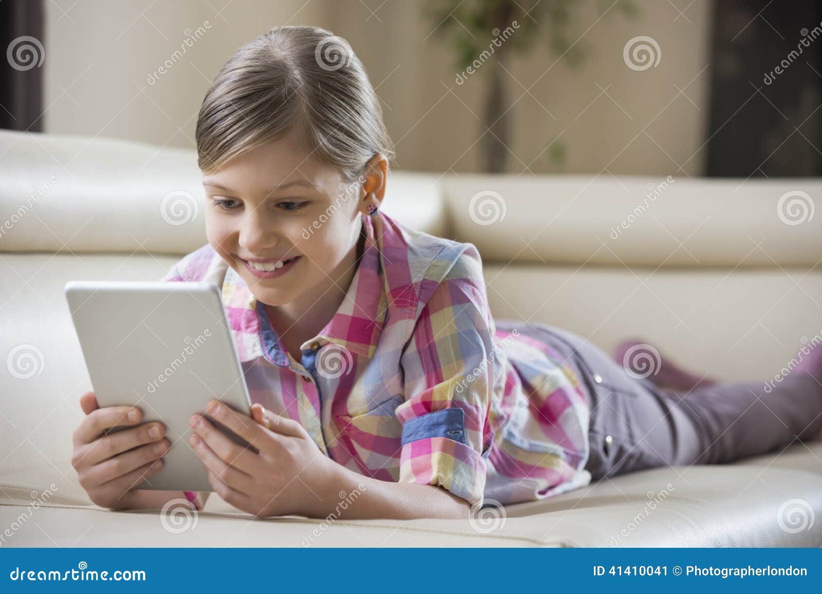 Smiling Girl Using Tablet PC while Lying on Sofa at Home Stock Image ...