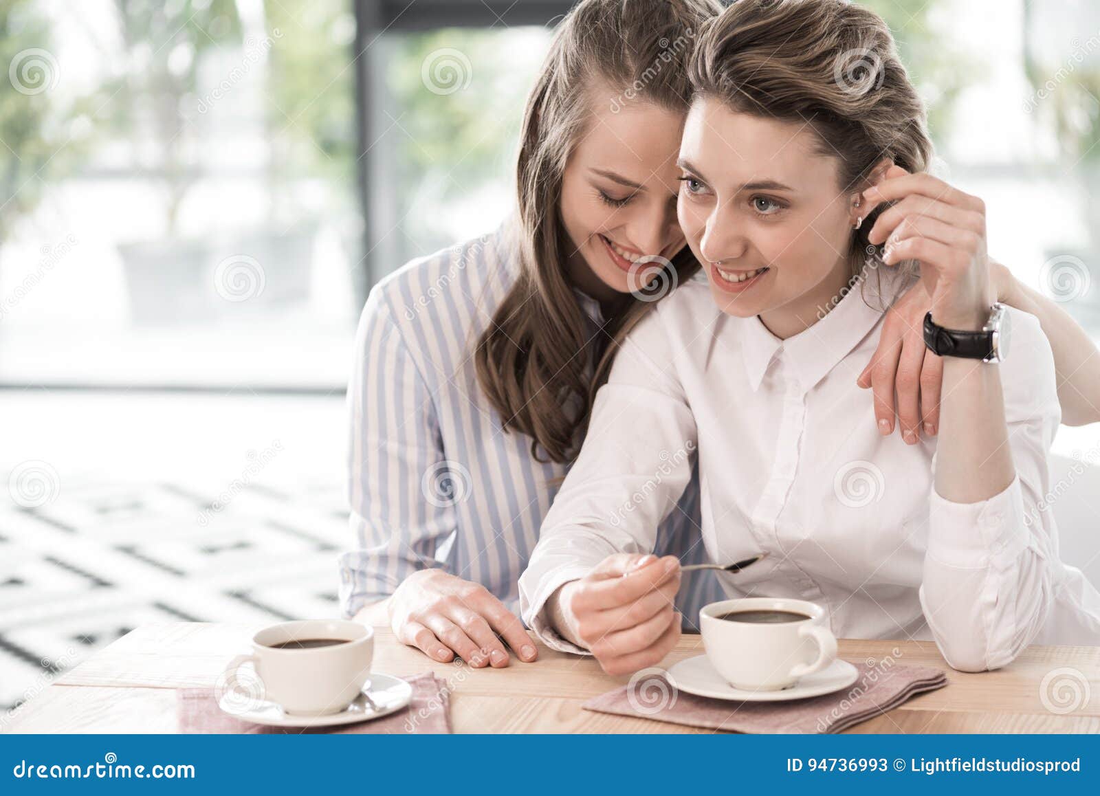 Smiling Girlfriends Drinking Coffee and Embracing at Cafe Stock Image ...