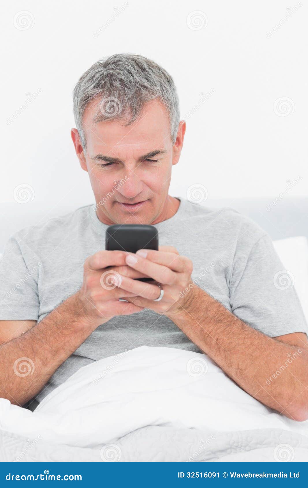 Smiling Grey Haired Man Sending a Text in Bed Stock Image - Image of ...