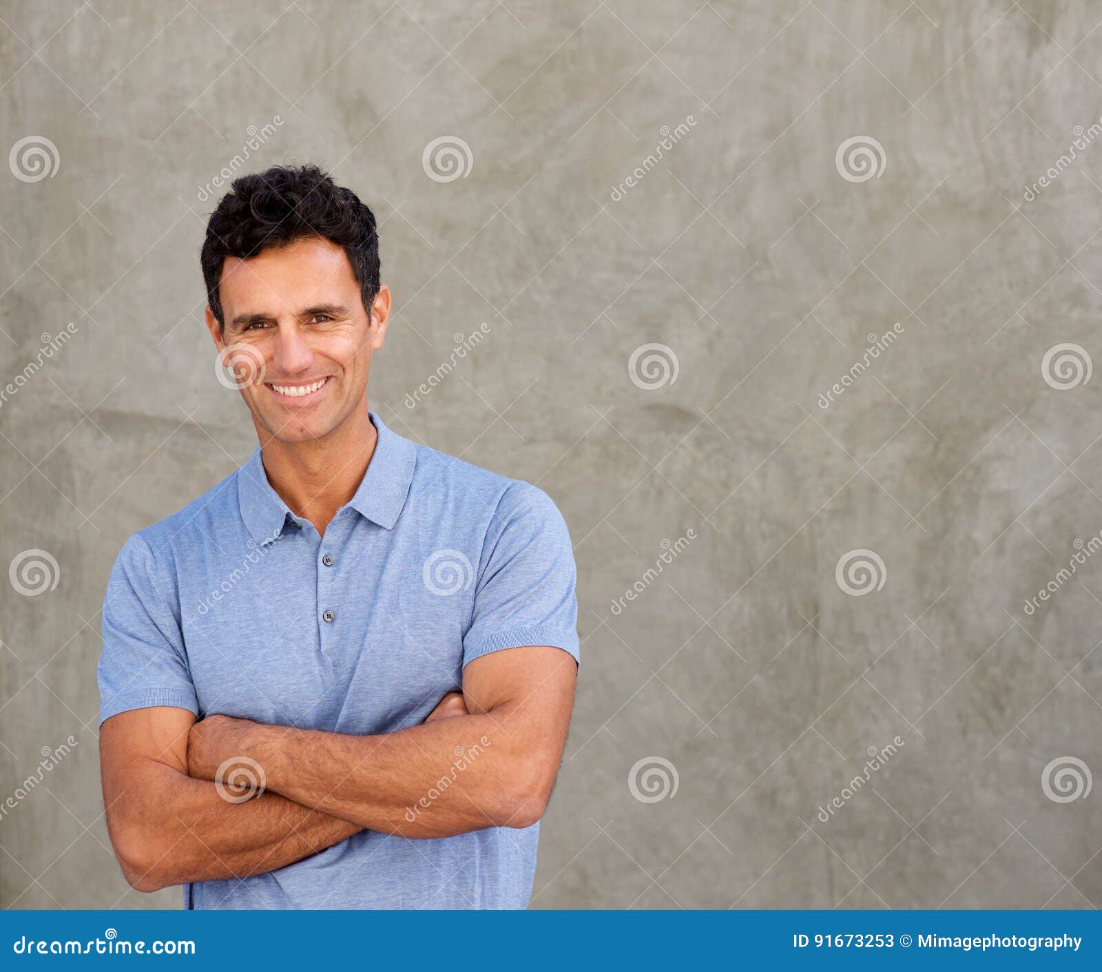 Smiling Handsome Man Standing By Wall With Arms Crossed Stock Image