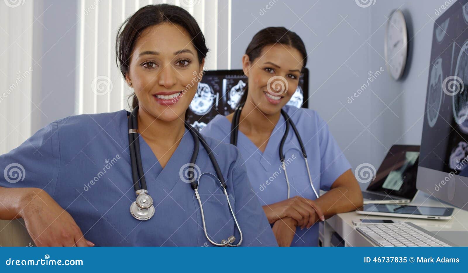 Smiling Hispanic and African American Nurses Sitting at Computer ...