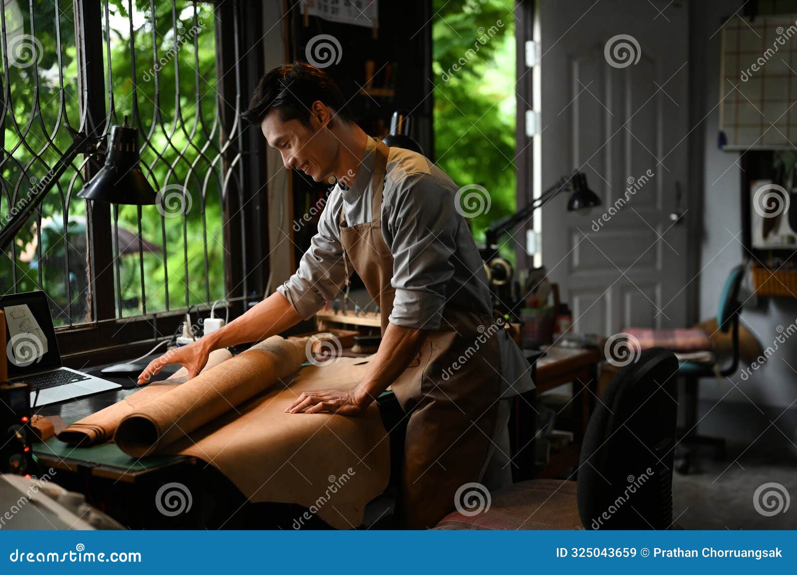 Smiling Leather Craftsman Rolls Natural Leather at His Workbench. Small Business and Leather ...