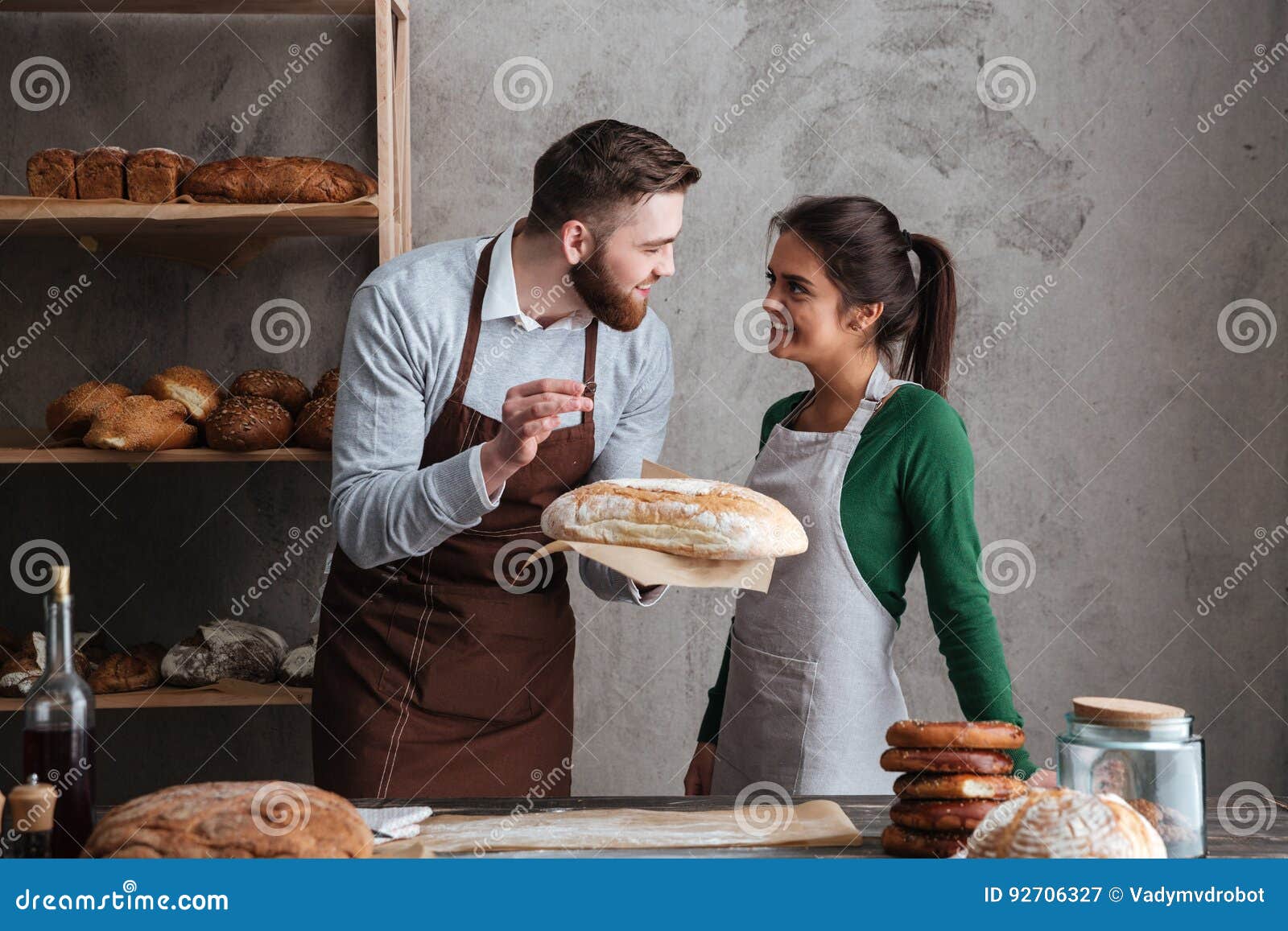Smiling Loving Couple Bakers Standing at Bakery Holding Bread Stock ...