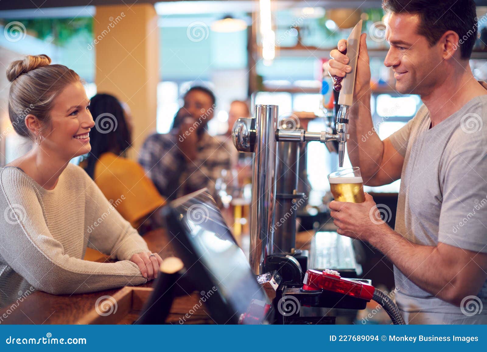 Smiling Male Bartender Behind Counter Serving Female Customer with Beer ...