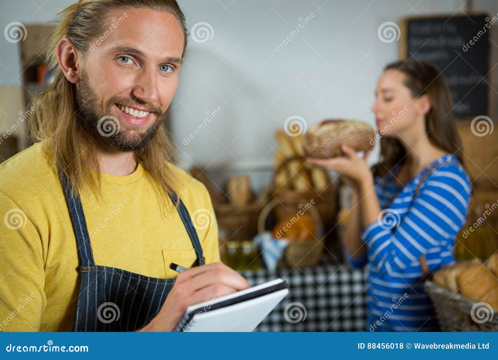 Smiling Male Staff Writing on Notepad at Counter Stock Photo - Image of ...