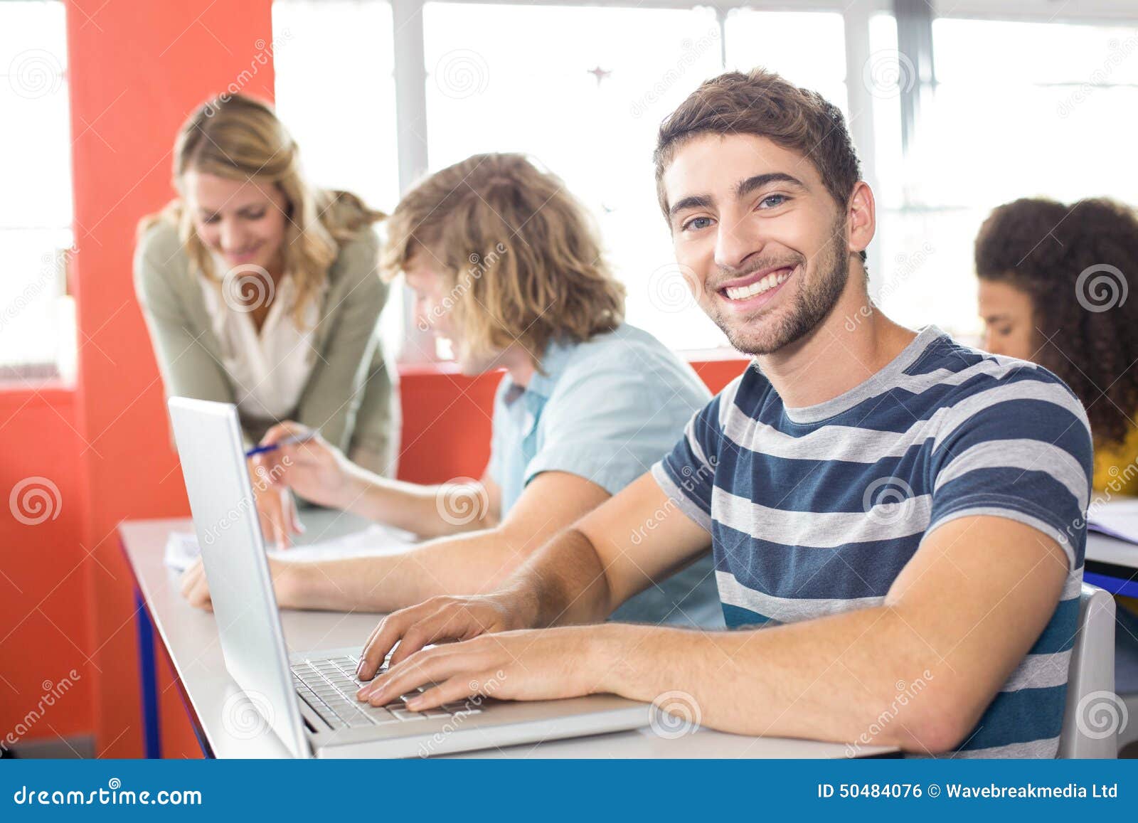 Smiling Male Student Using Laptop in Classroom Stock Photo - Image of ...
