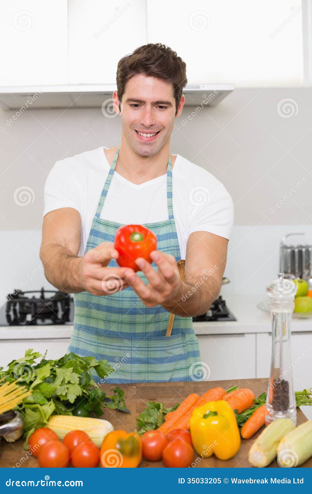 Smiling Man Holding Out Bell Pepper with Vegetables in Kitchen Stock ...