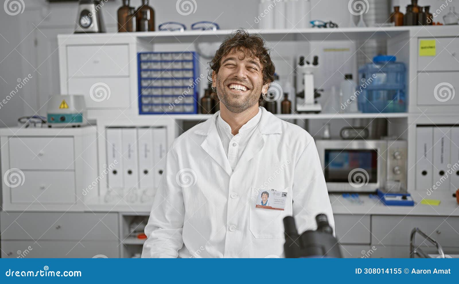 Smiling Man in Lab Coat Standing Inside a Laboratory with Equipment and ...