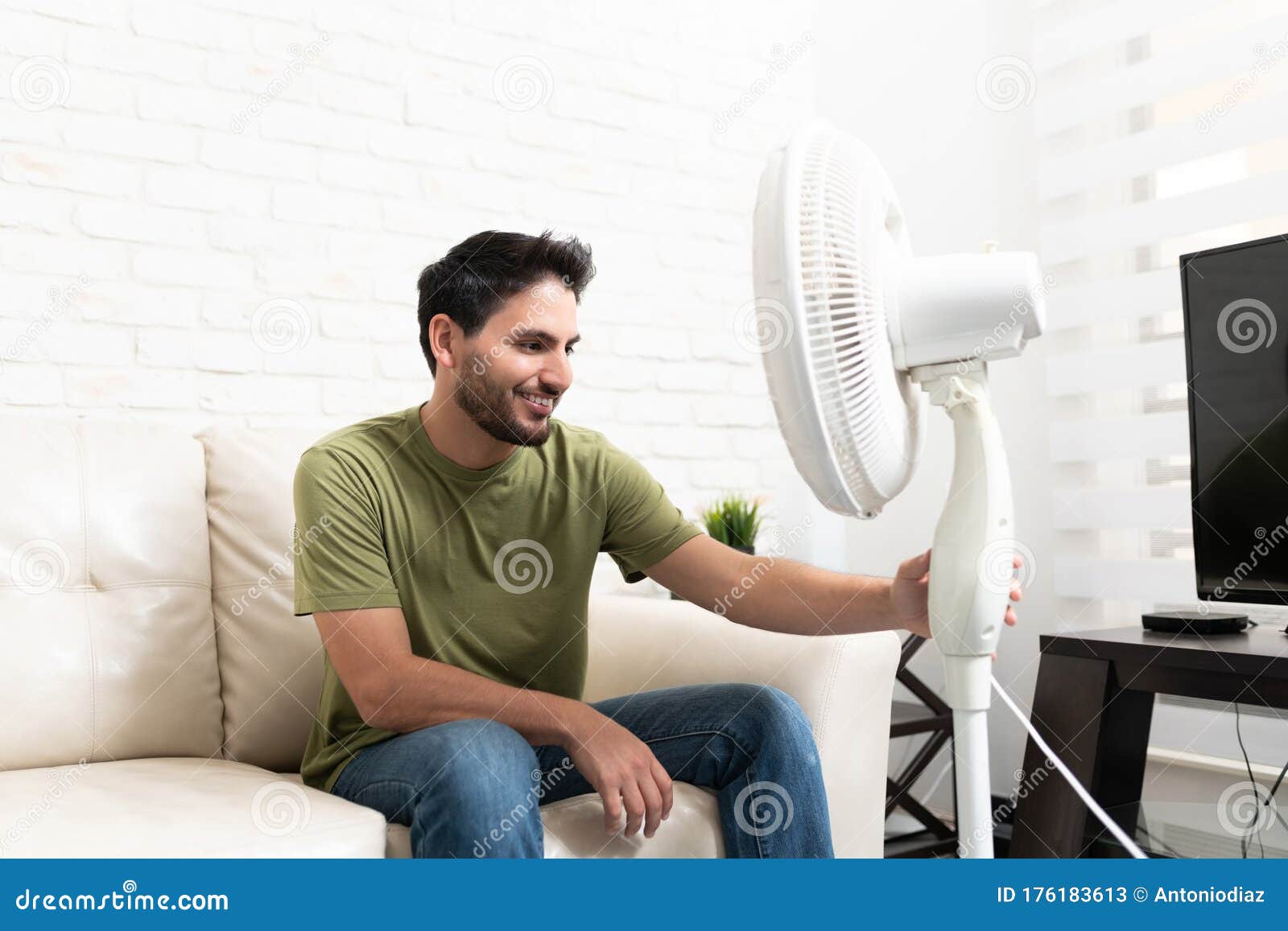 Smiling Man Sitting in Front of Fan at Home Stock Image - Image of warm ...