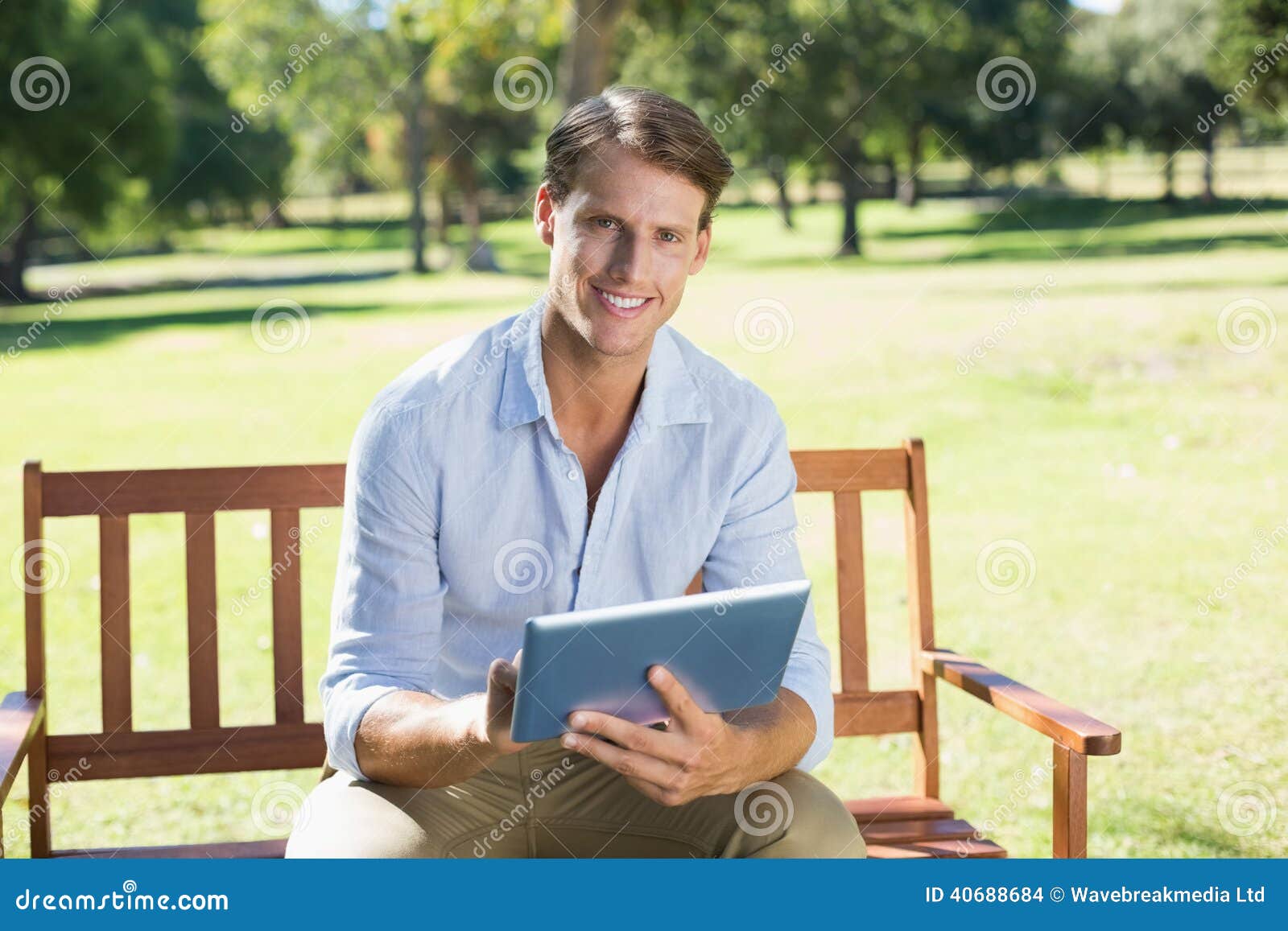 Smiling Man Sitting on Park Bench Using Tablet Looking at Camera Stock ...