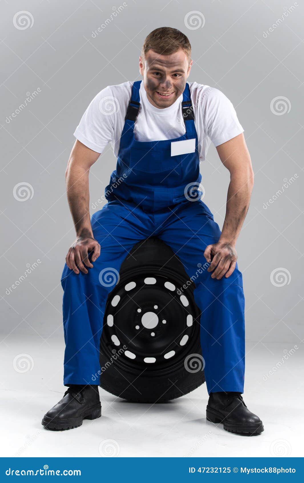Smiling Man Sitting on Tire on Grey Background. Stock Image - Image of ...