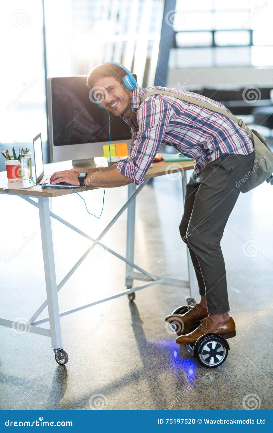 Smiling Man Standing on Hoverboard and Using Laptop in Office Stock ...