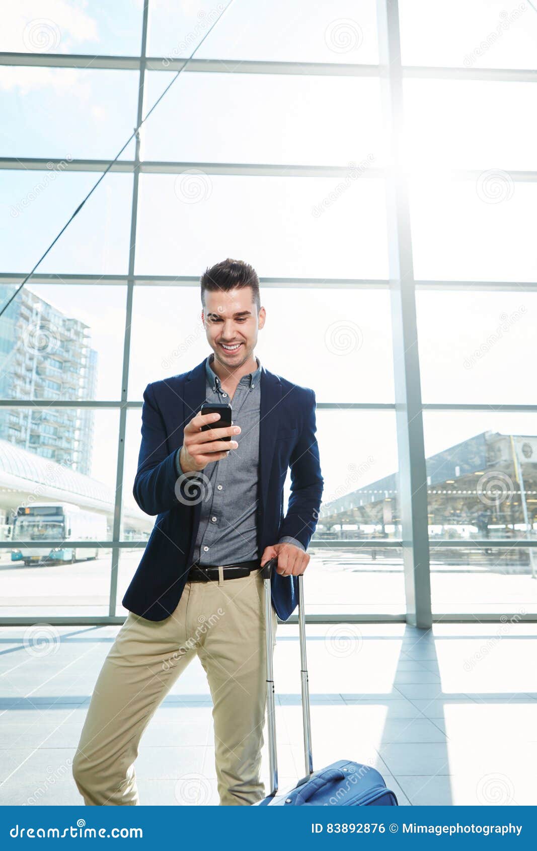 Smiling Man Standing in Station with Smart Phone and Suitcase Stock ...