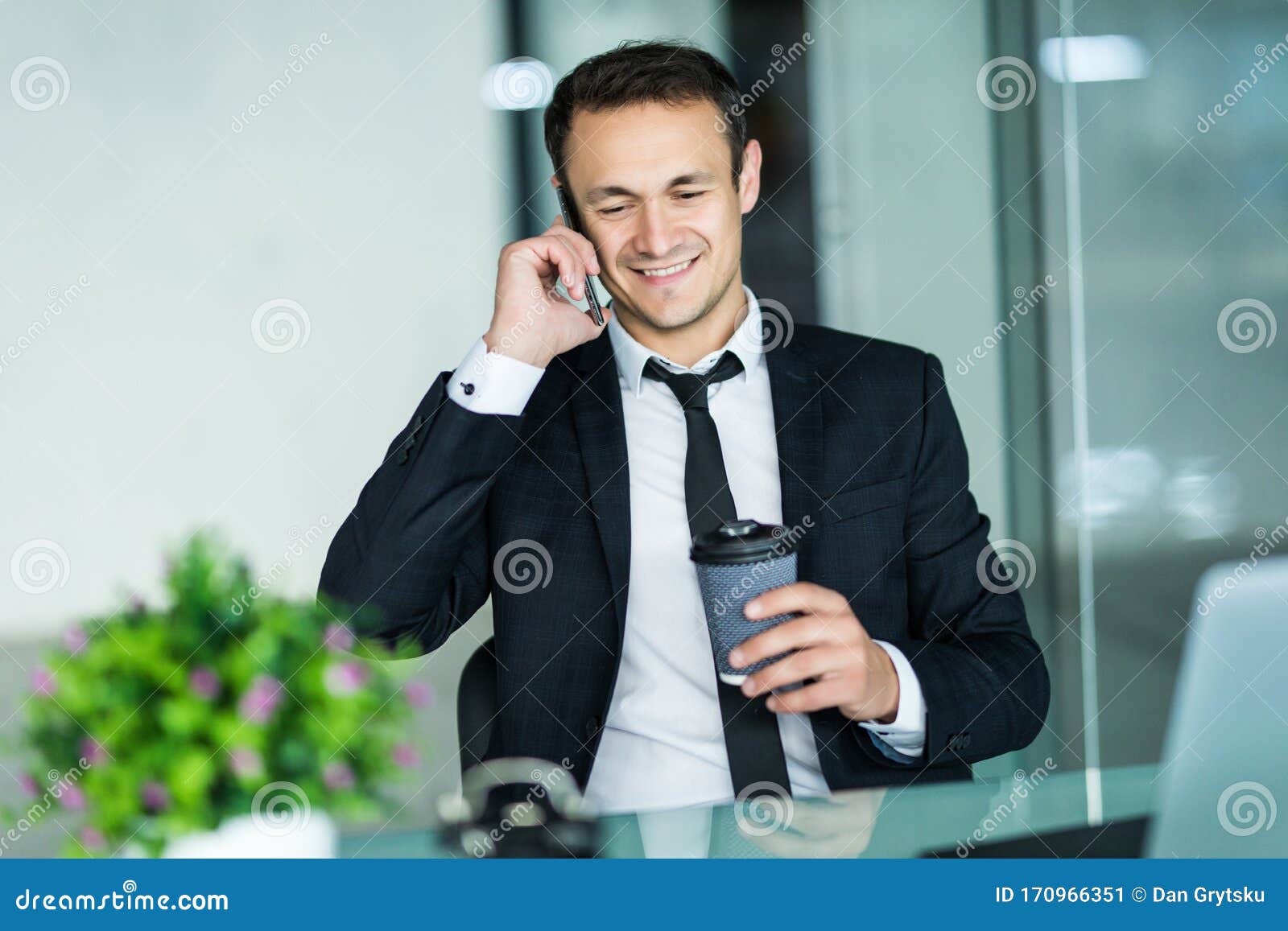 Smiling Man Talking on Mobile Phone while Using Laptop Computer at Desk ...