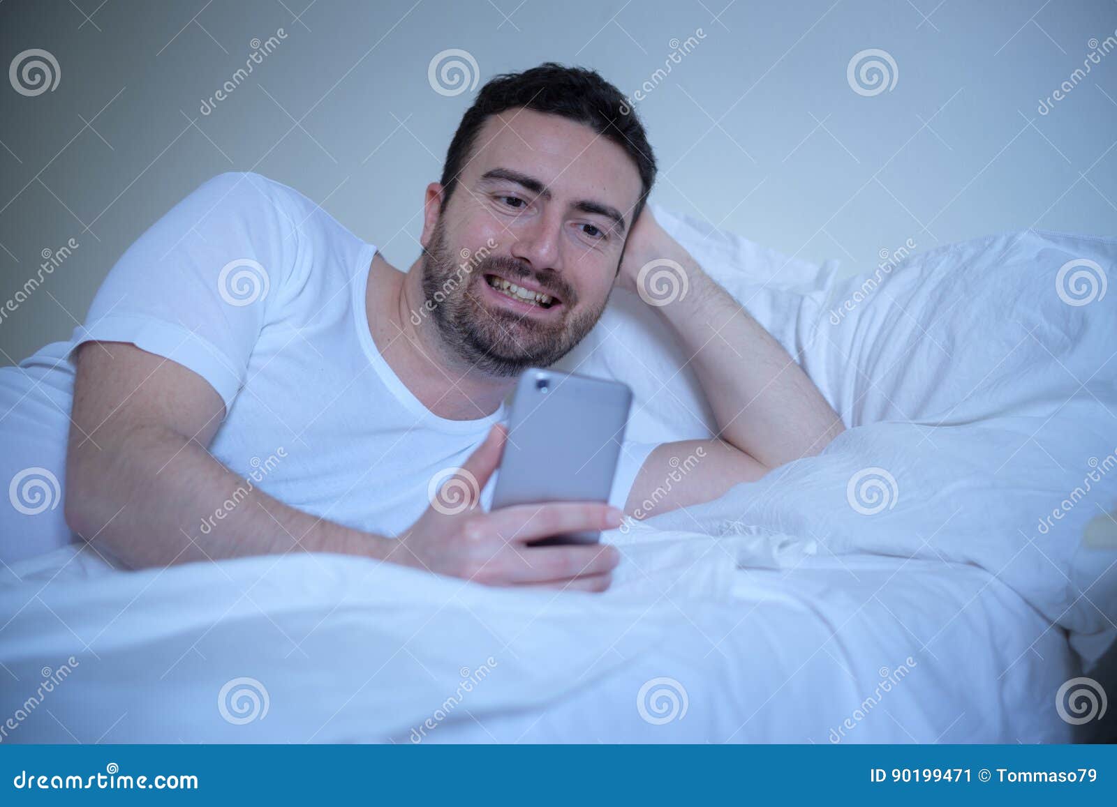 Smiling Man Using His Smart-phone Lying in Bed Stock Image - Image of ...