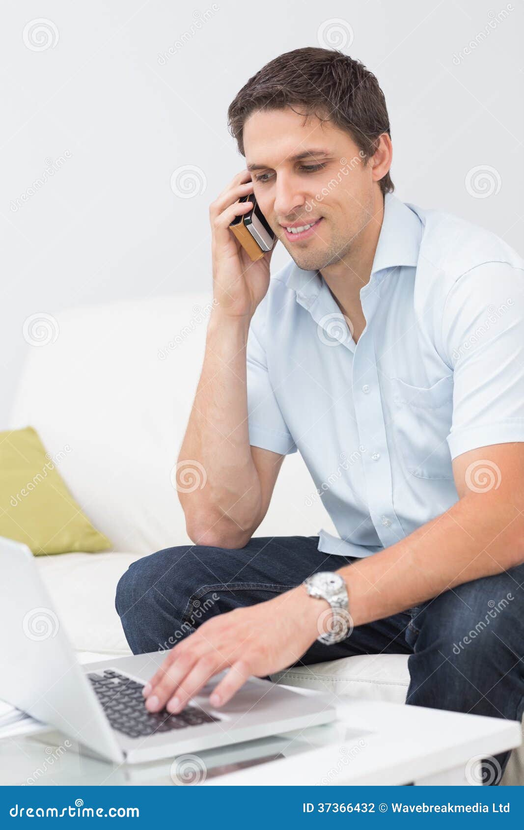 Smiling Man Using Laptop and Cellphone in the Living Room Stock Photo ...
