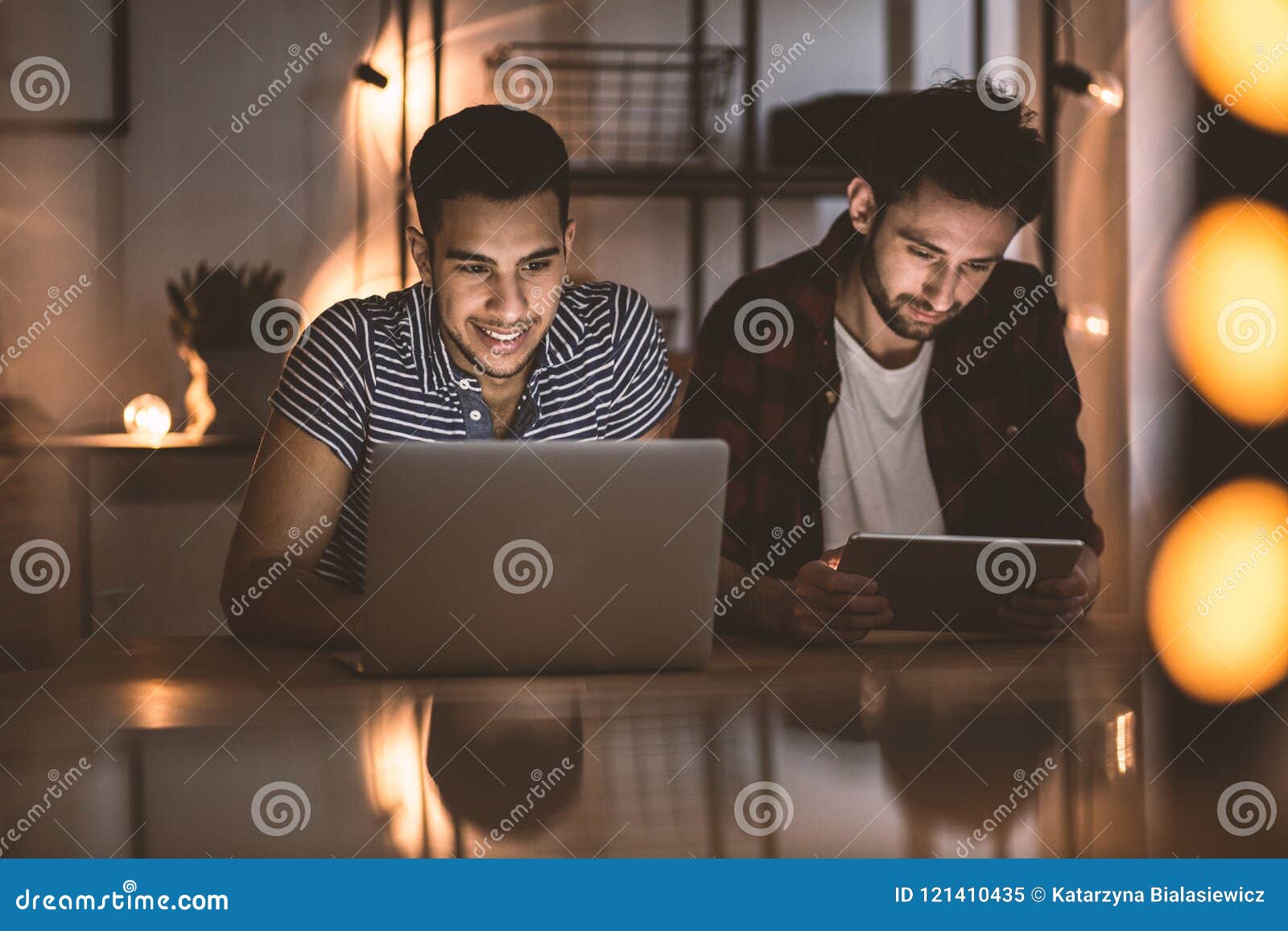 Smiling Man Using Laptop while His Friend Playing on Tablet. Pro Stock ... Smiling Man Using Laptop while His Friend Playing on Tablet. Pro Stock ...
