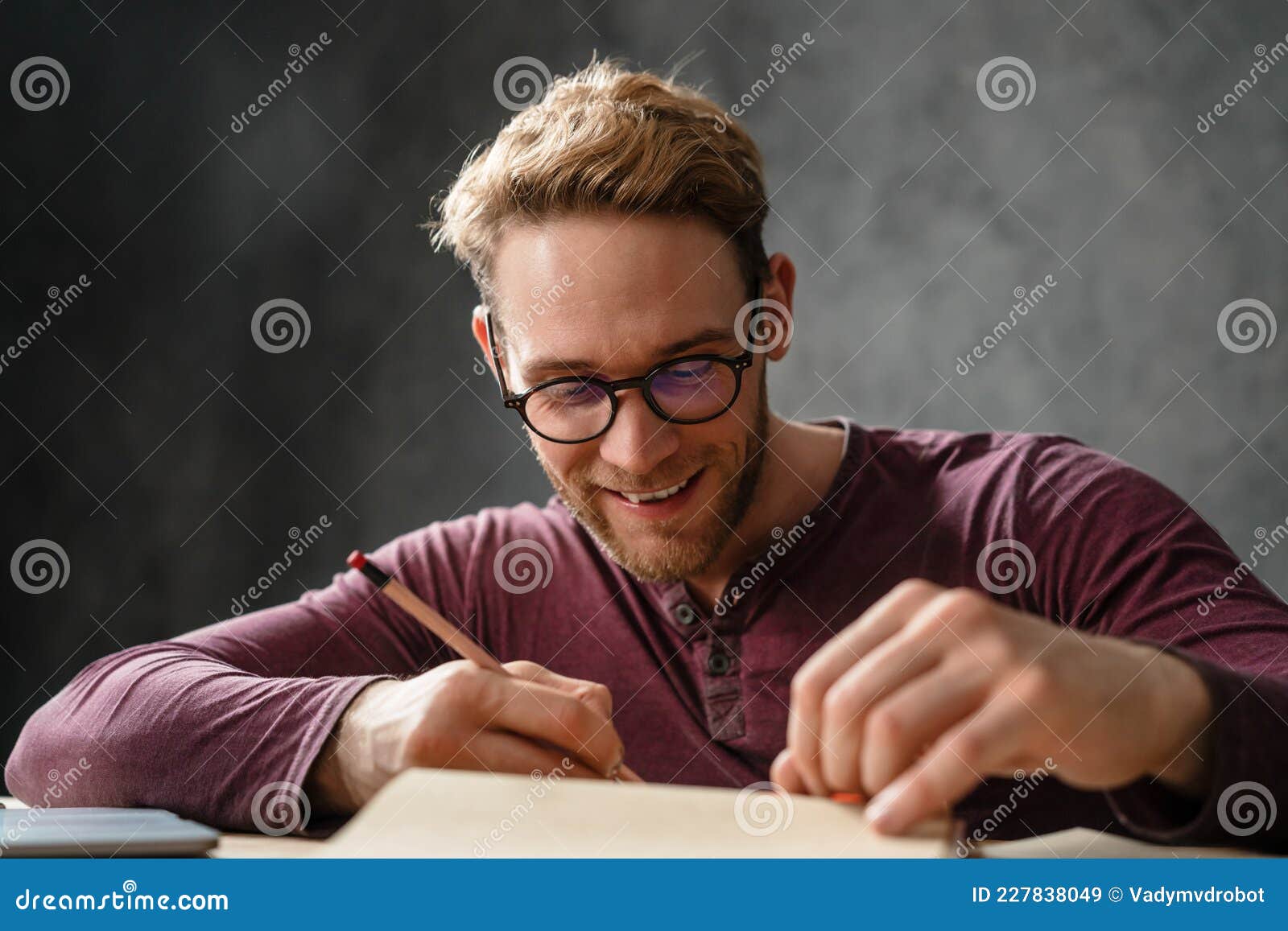 The Smiling Man Writing Something while Sitting at the Table in the ...
