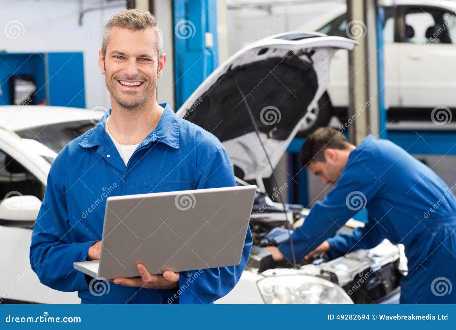 Smiling Mechanic Using a Laptop Stock Photo - Image of expertise, blue ...