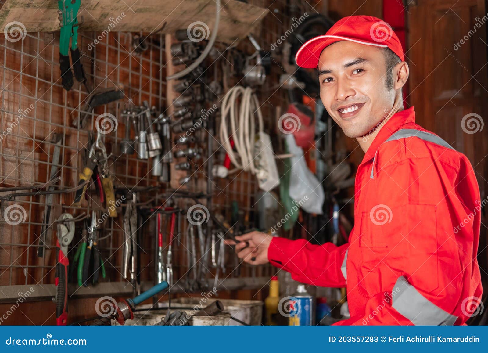Smiling Mechanic in a Wearpack Puts His Workshop Equipment on a Rack ...