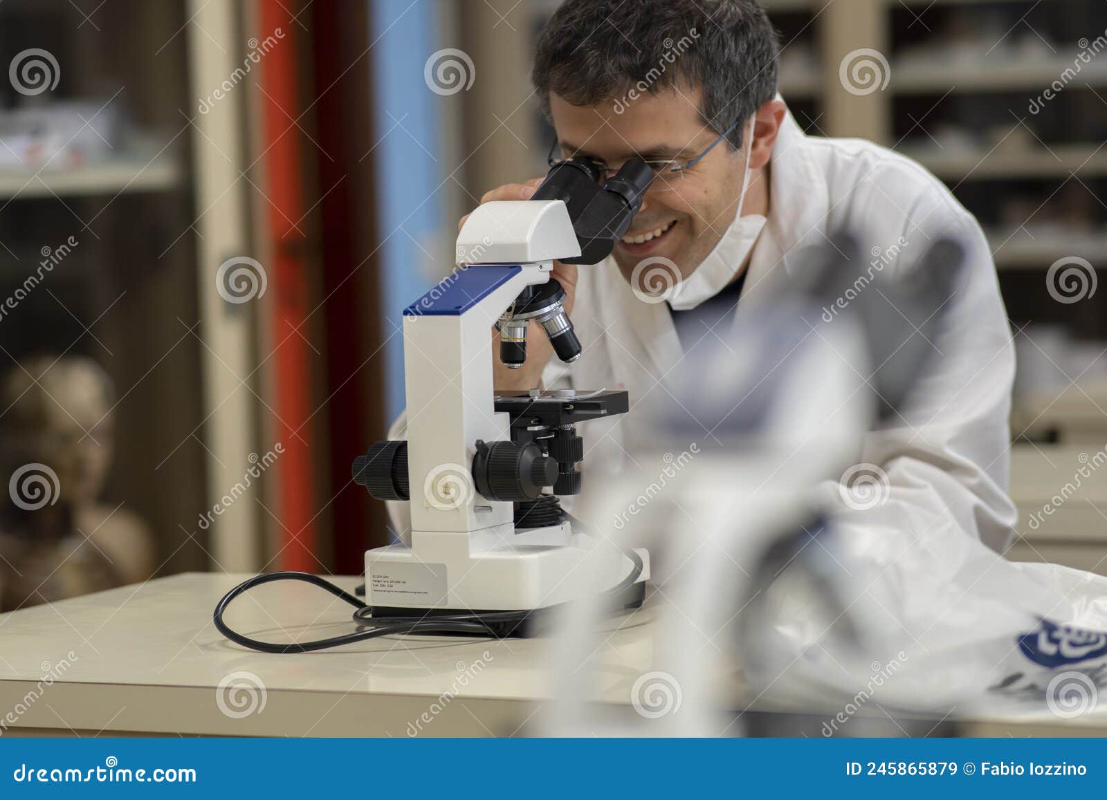 Smiling Microbiologist at Work into Laboratory Using a Microscope Stock ...