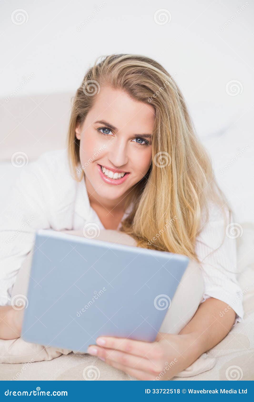 Smiling Model Using Her Tablet Lying on Cosy Bed Stock Photo - Image of ...