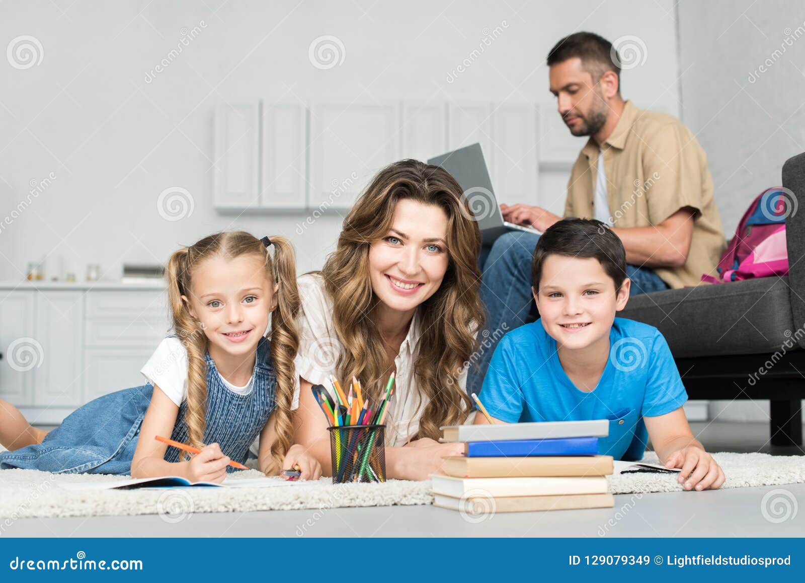 Smiling Mother and Kids Looking at Camera while Doing Homework Together ...