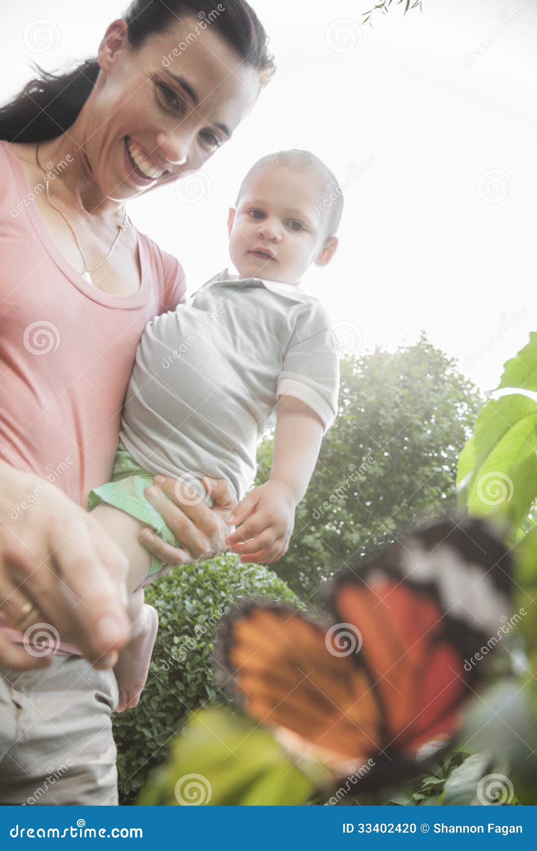 Smiling Mother and Son Pointing and Looking at a Butterfly in the ...
