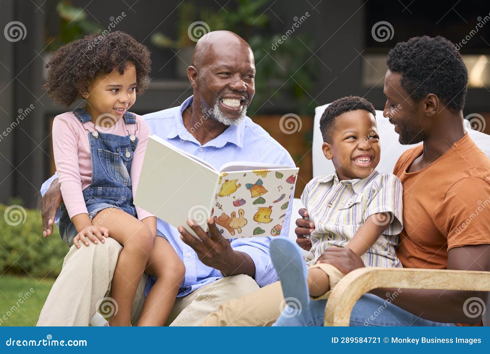 Smiling Multi-Generation Family Reading Book in Garden Together Stock ...