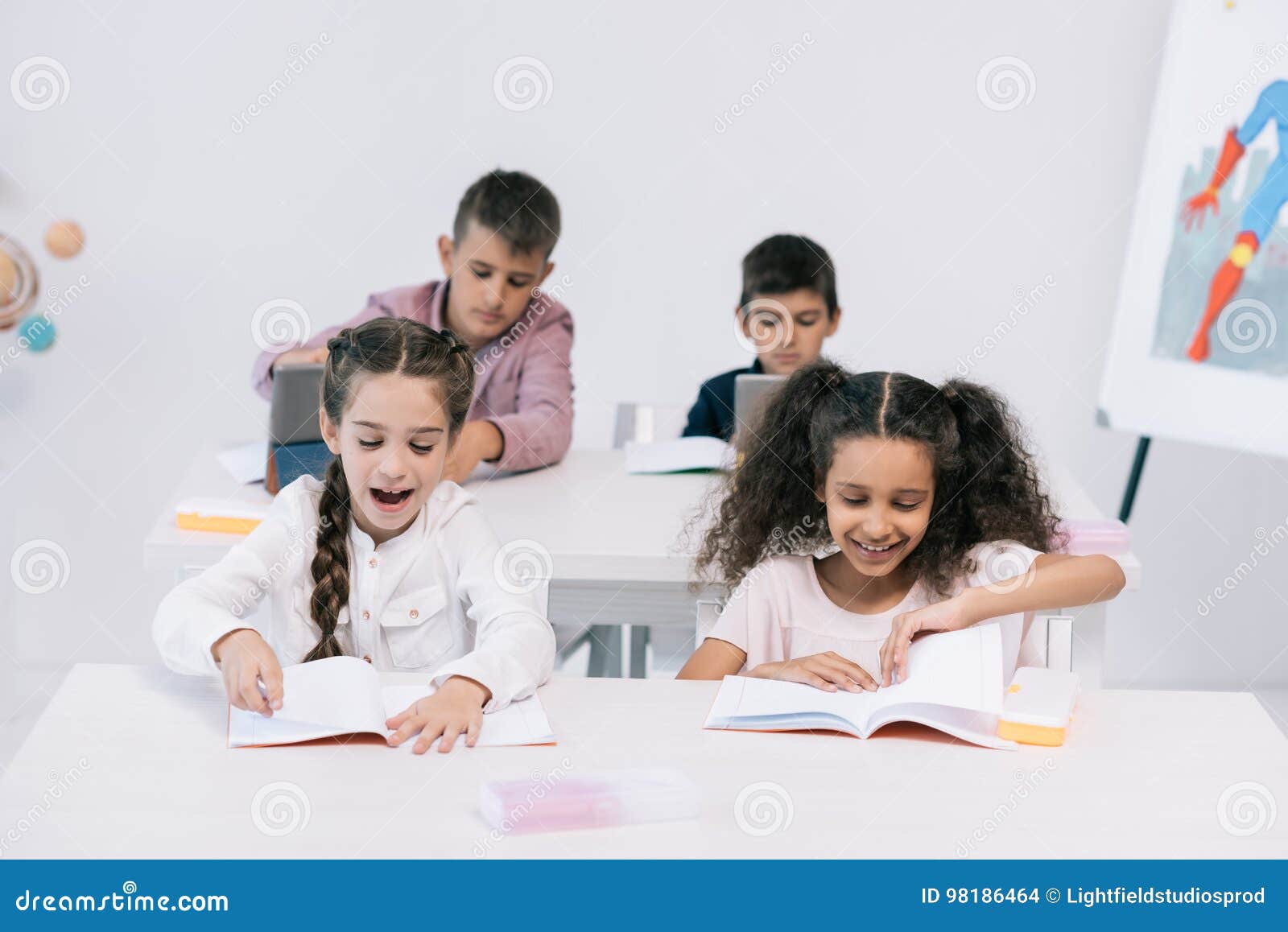 Smiling Multiethnic Pupils Studying with Textbooks in Classroom Stock ...