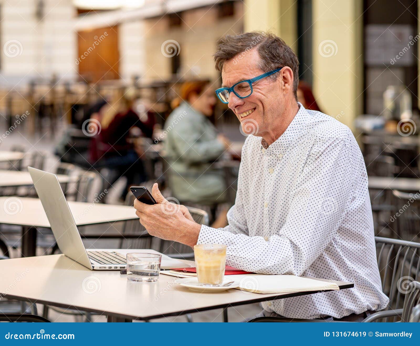 Smiling Old Man Checking Smart Phone while Working on Computer in ...