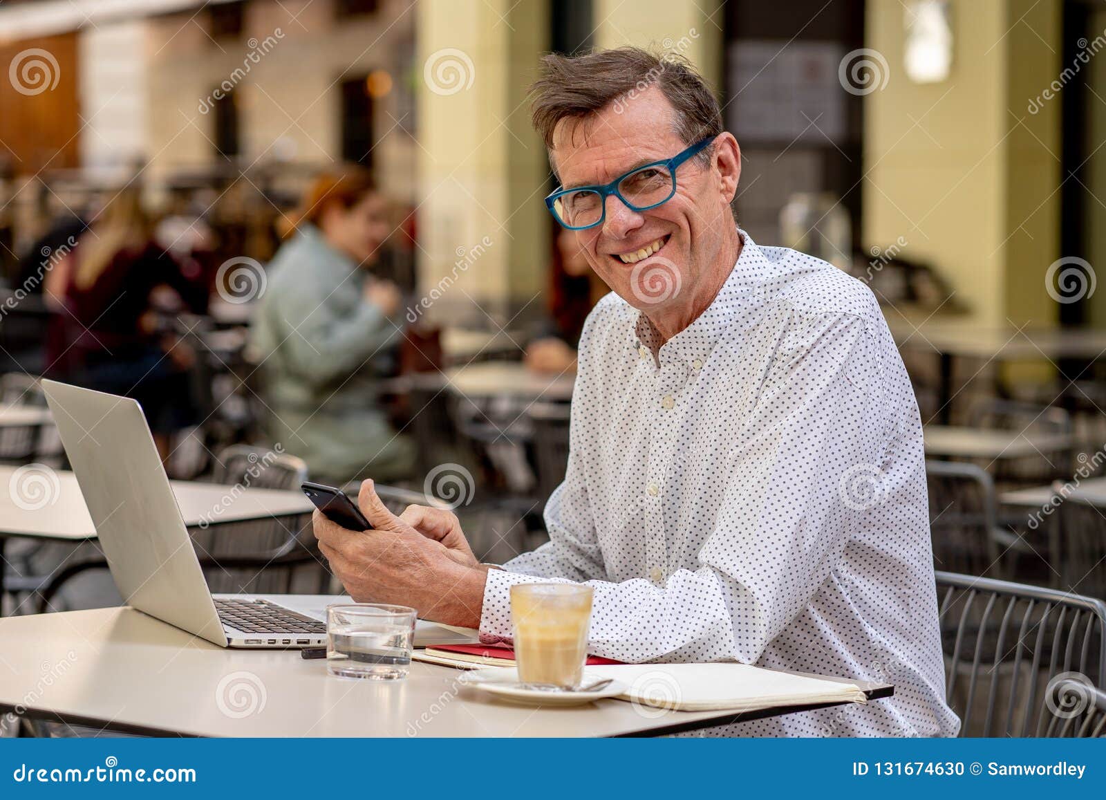 Smiling Old Man Checking Smart Phone while Working on Computer in ...