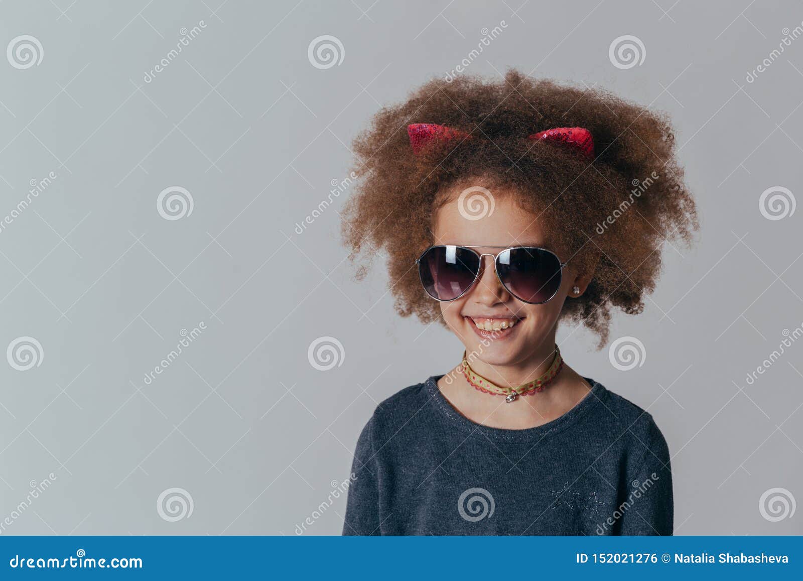 Smiling Pretty Girl With Curly Hair In Sunglasses On Gray Background