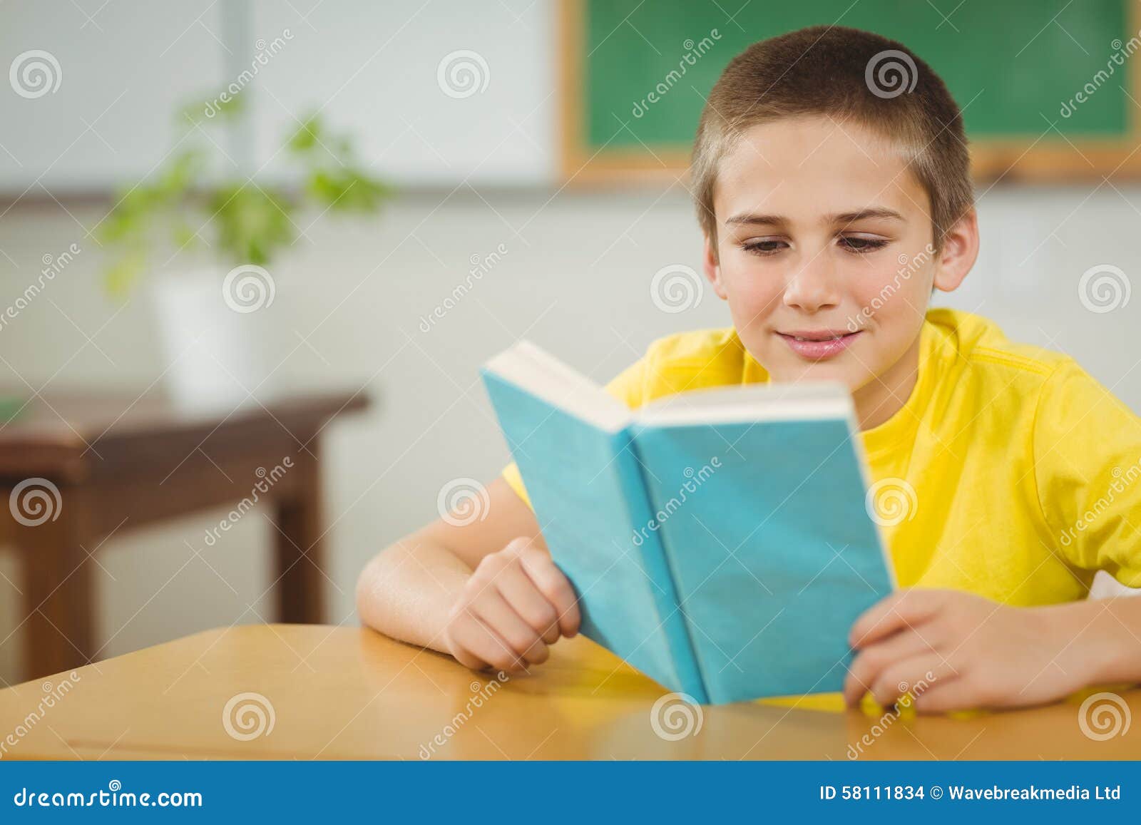 Smiling Pupil Reading Book in a Classroom Stock Photo - Image of ...