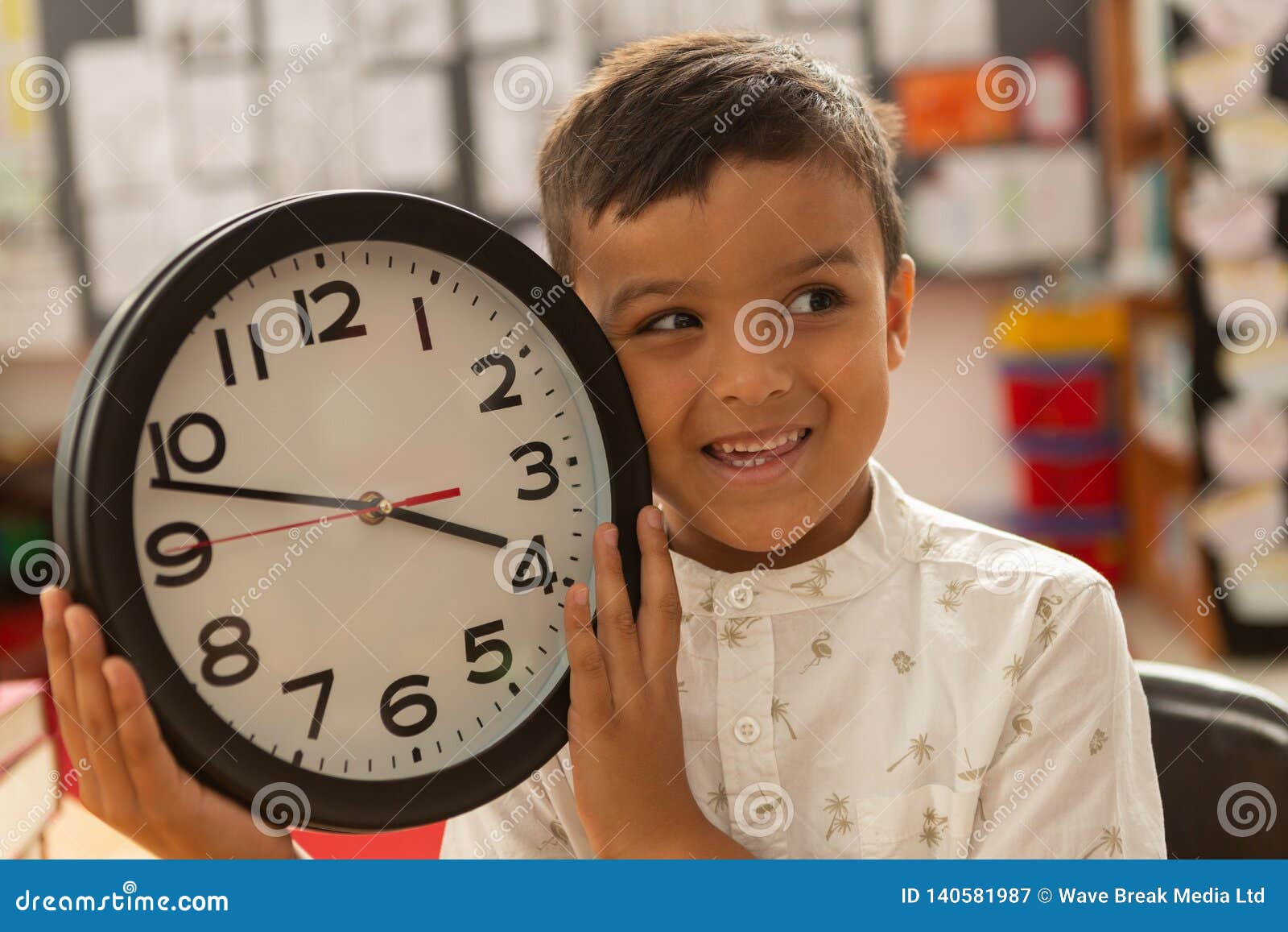 Smiling Schoolboy with Wall Clock Looking Away in a Classroom Stock ...