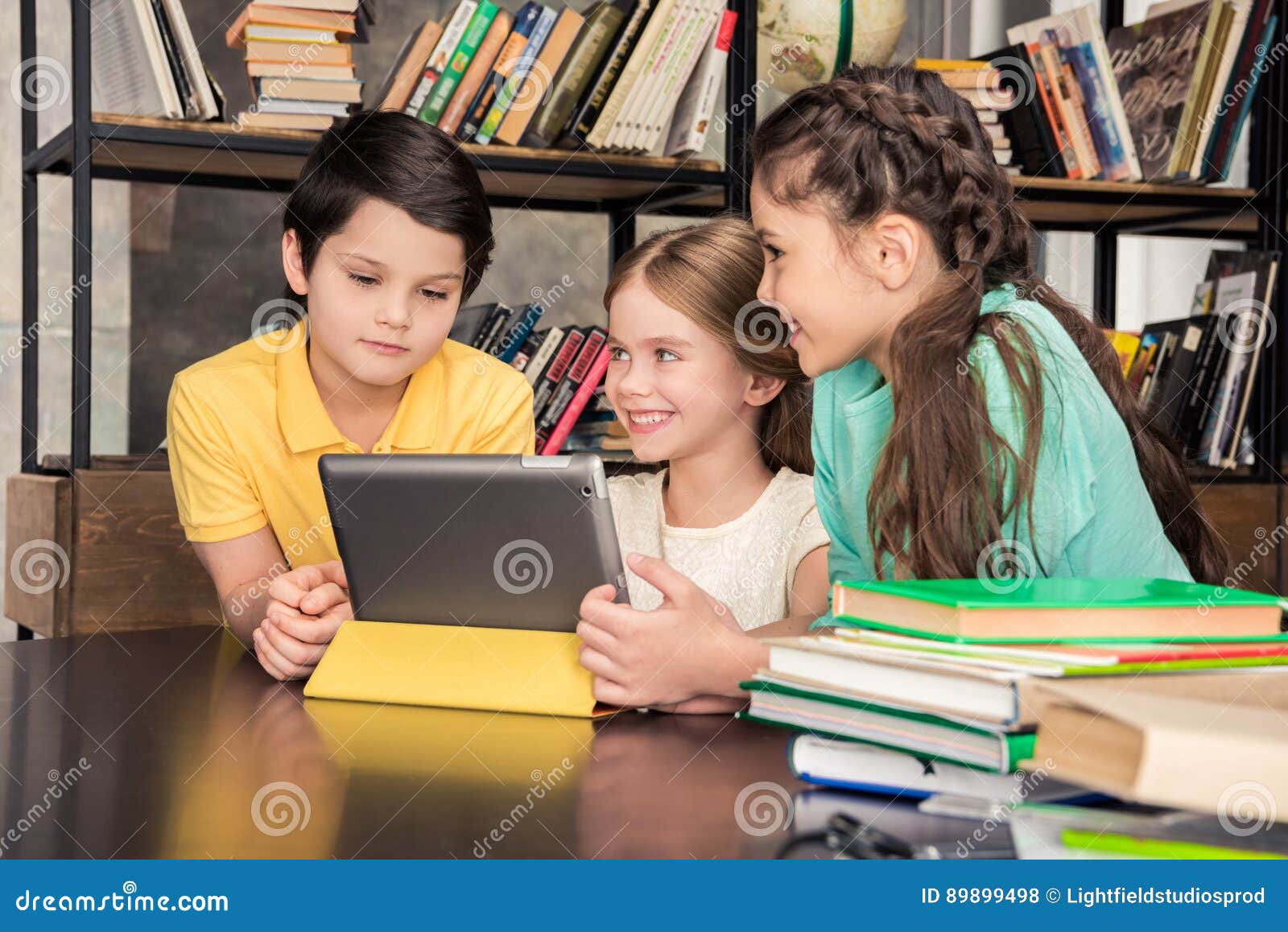 Smiling Schoolchildren Using Digital Tablet in Library Stock Photo ...