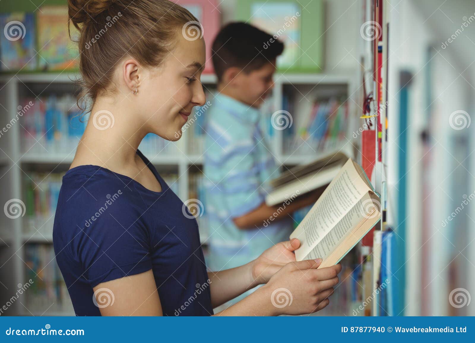 Smiling Schoolgirl Reading Book in Library Stock Photo - Image of ...