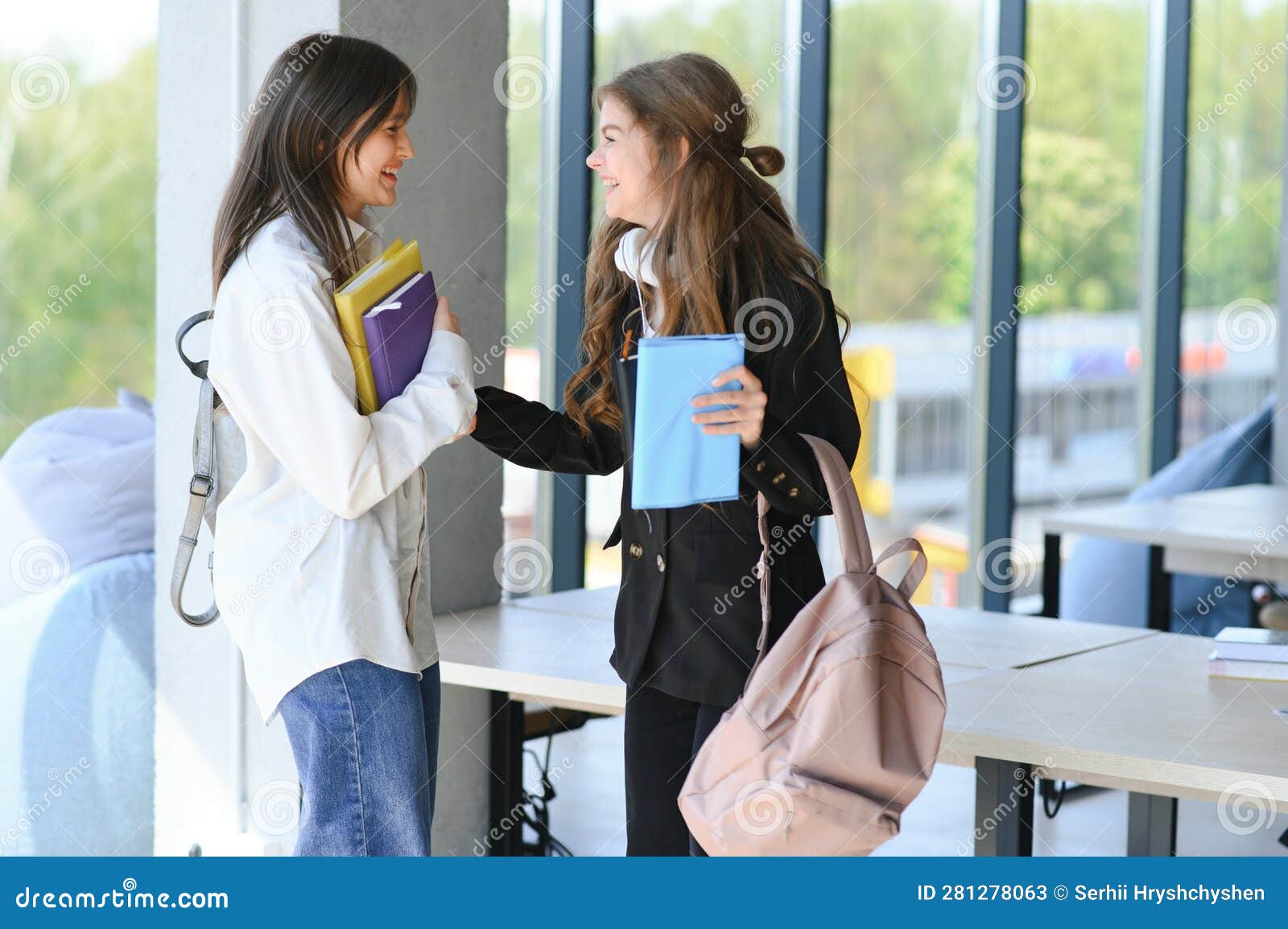 Smiling Schoolgirls are Talking about Homework at the Desk in the Class ...