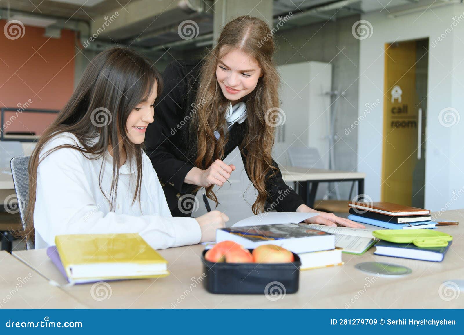 Smiling Schoolgirls are Talking about Homework at the Desk in the Class ...
