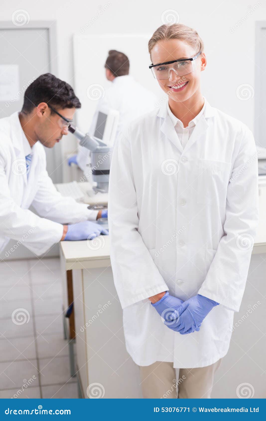 Smiling Scientist Looking at Camera while Colleagues Working Behind ...