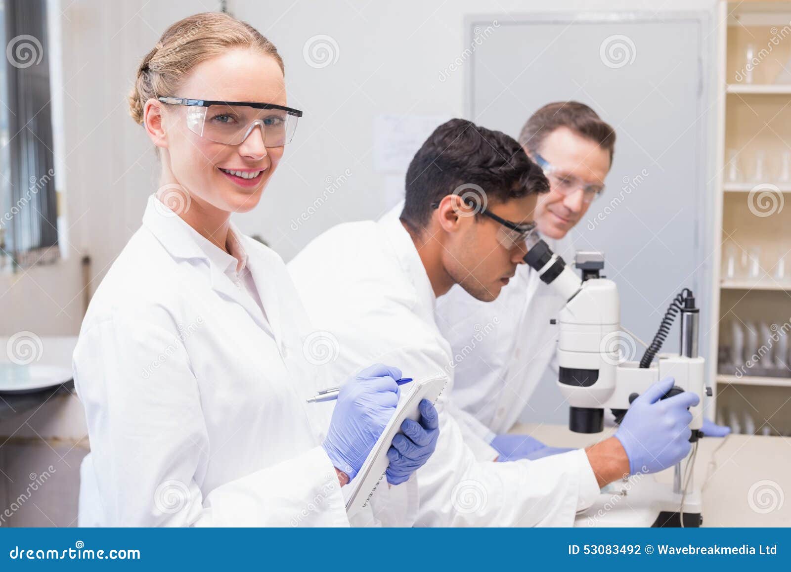 Smiling Scientist Looking At Camera While Colleagues Working With ...
