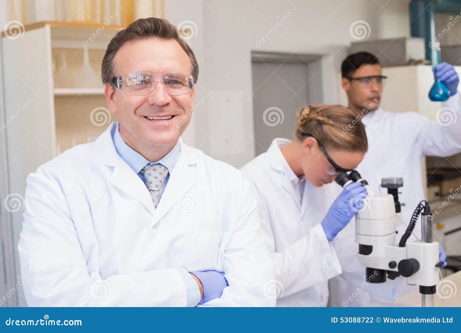 Smiling Scientist Looking At Camera While Colleagues Working With ...