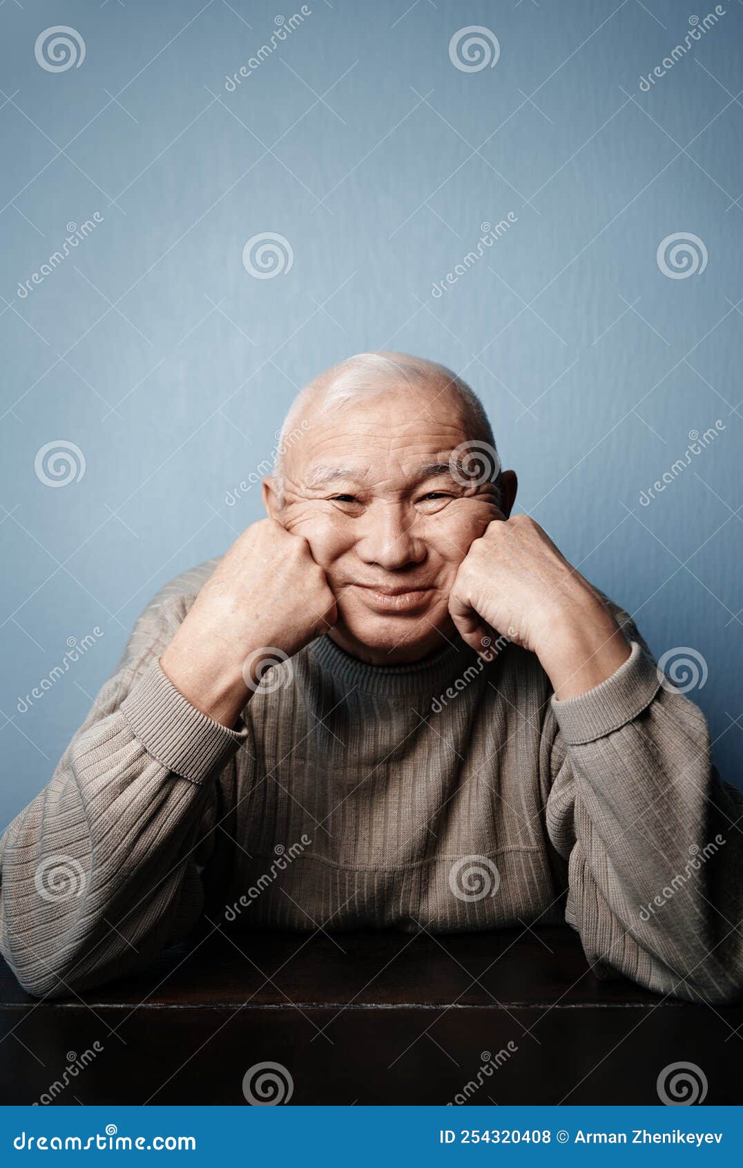 Smiling Senior Man Sitting At The Table And Looking At Camera Stock