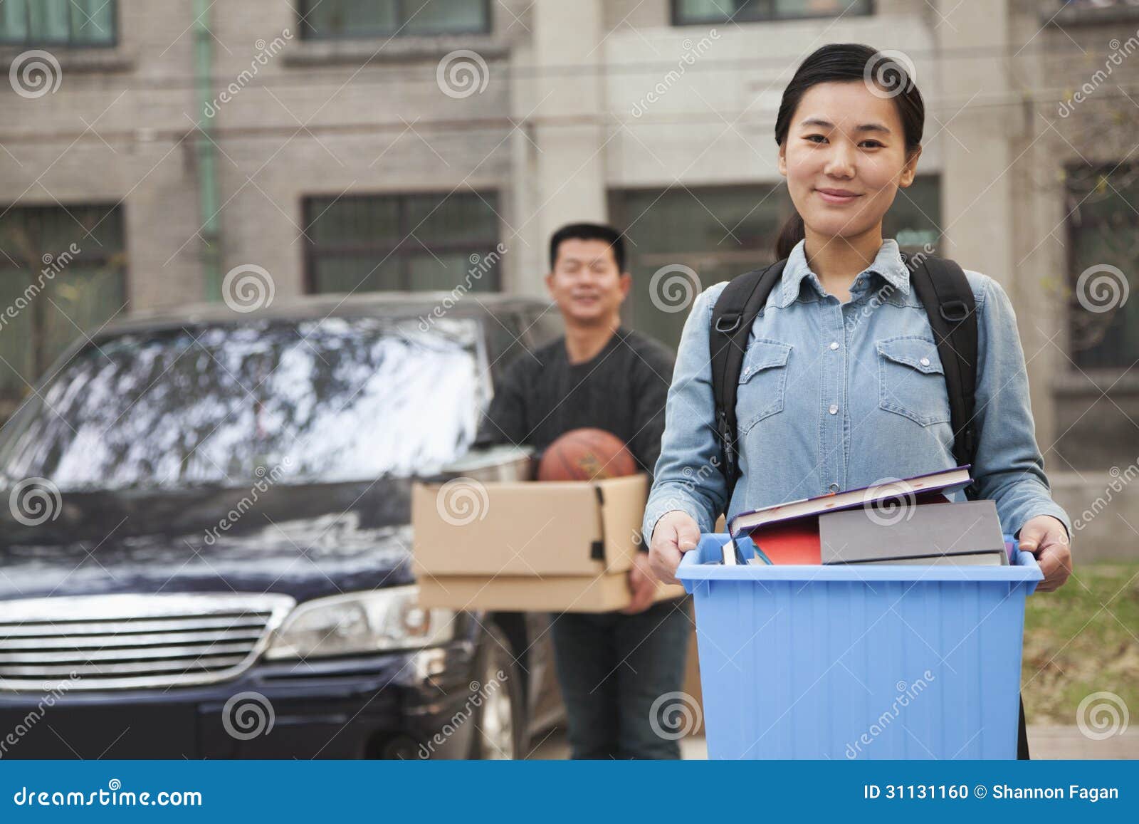 Smiling Student Portrait in Front of Dormitory at College, Holding Bin ...