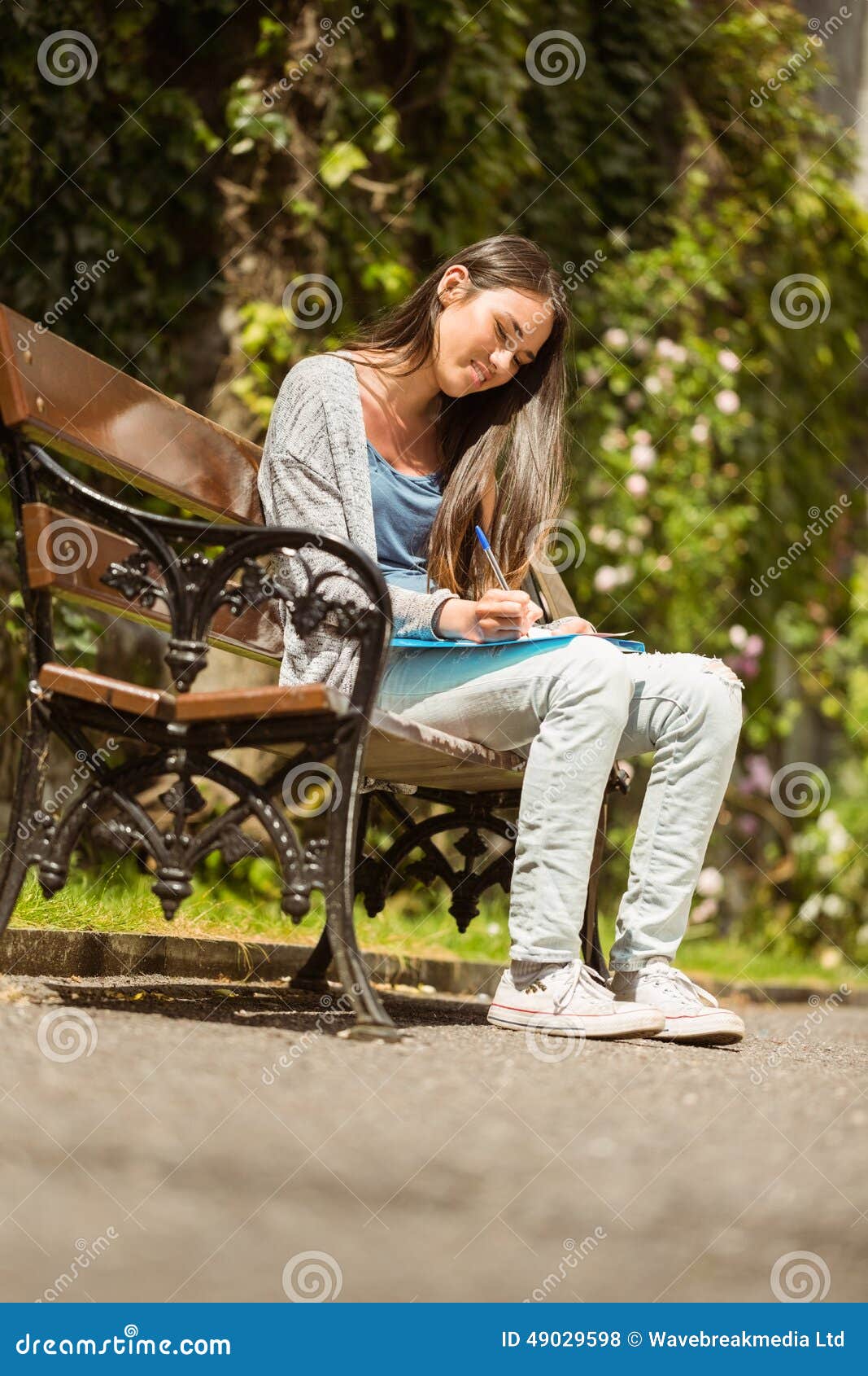 Smiling Student Sitting on Bench and Writing on Notepad Stock Photo ...
