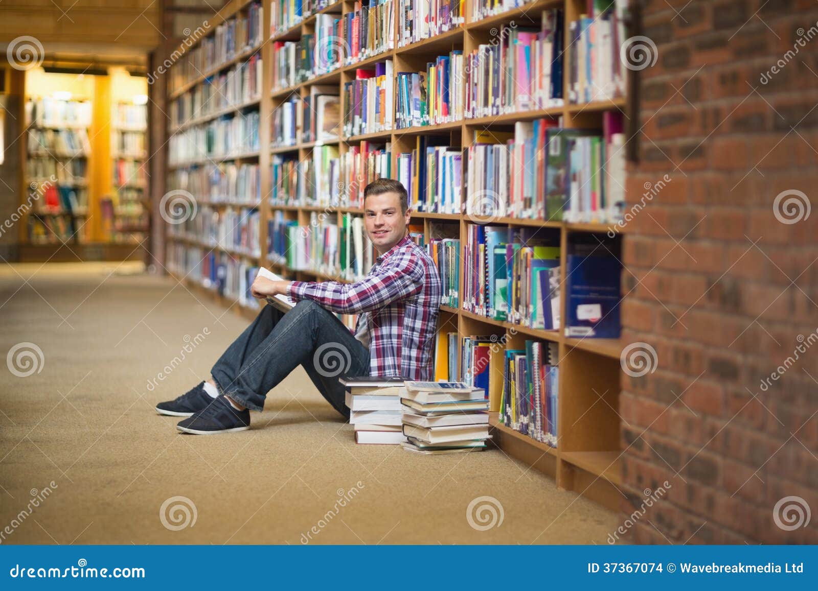 Smiling Student Sitting on Library Floor Reading Stock Photo - Image of ...