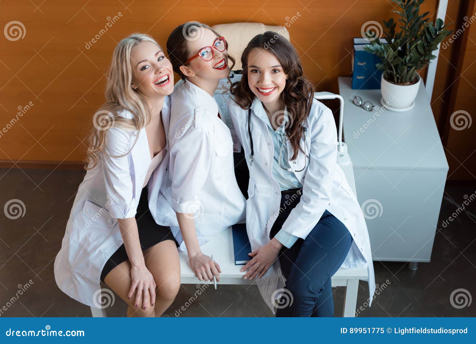 Smiling Three Doctors Sitting on Table in Cabinet Stock Image - Image ...