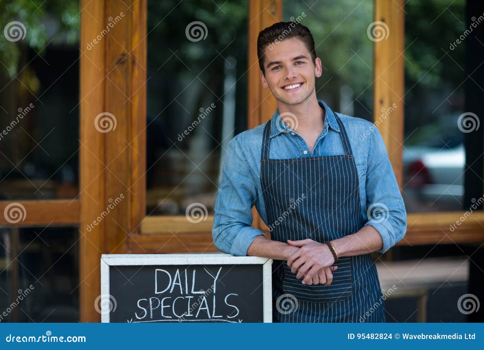 Smiling Waiter Leaning on Menu Board Outside the Cafe Stock Photo ...