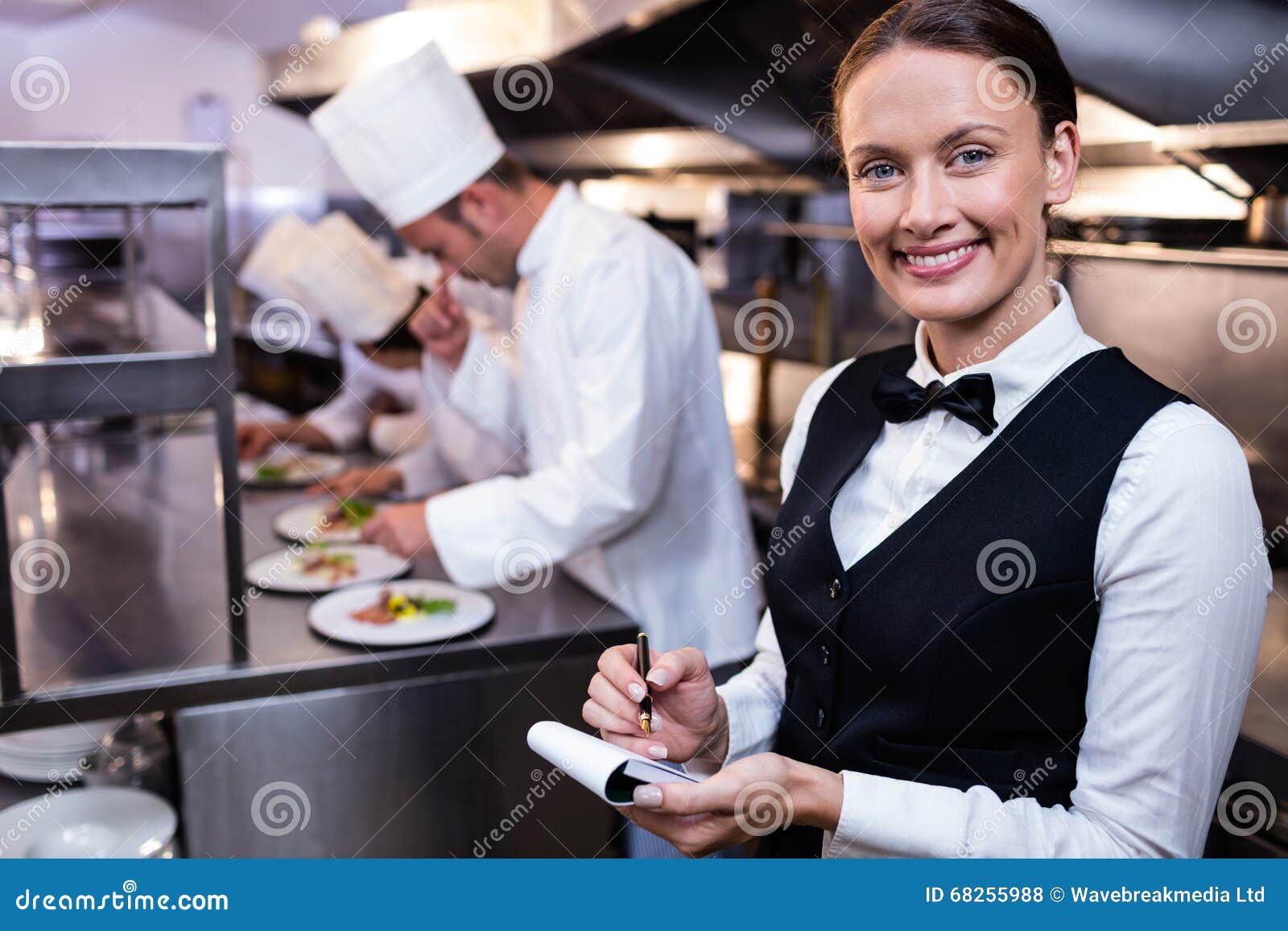 Smiling Waitress with Note Pad in Commercial Kitchen Stock Photo ...